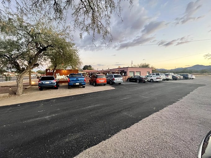 The parking lot at sunset reveals the true measure of a restaurant's worth—a full house of cars whose owners have temporarily abandoned the outside world.