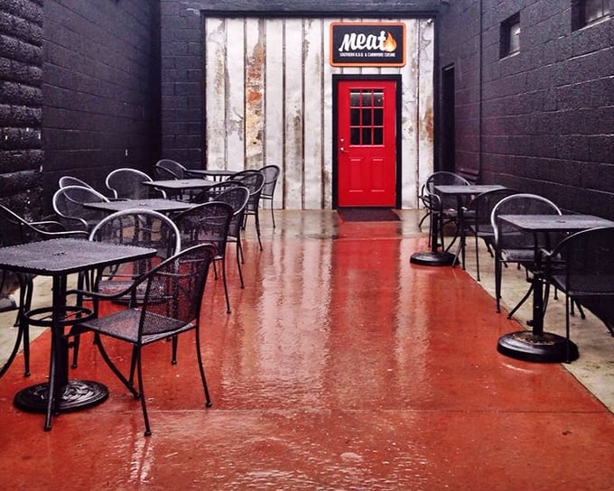 The patio—where the red door stands like a portal to meat paradise. Rain or shine, this space promises smoky delights ahead.