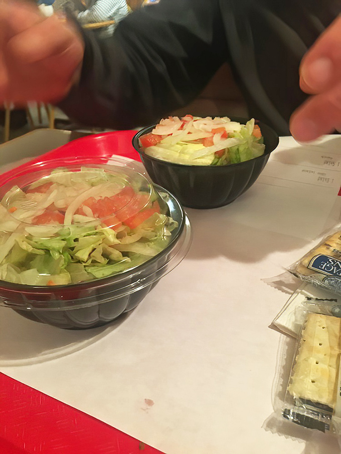 Simple side salads in plastic bowls—because sometimes you need a token vegetable before diving into pizza paradise.