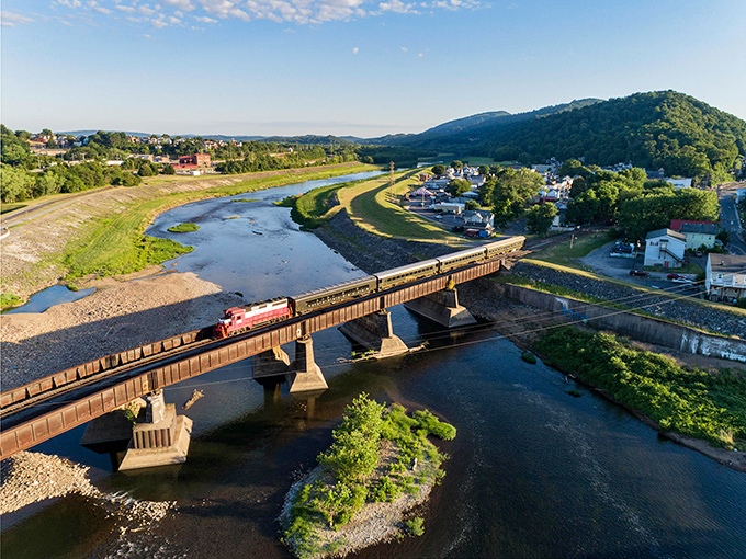 The little engine that could—and definitely does. This aerial view captures the train crossing the river like a scene from a model railroad enthusiast's dream come true.