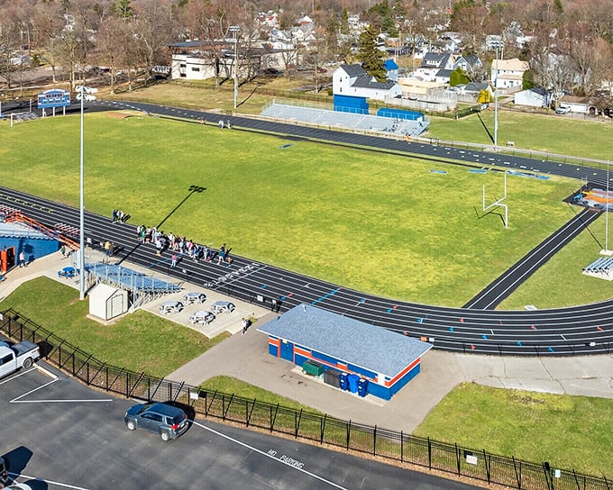The high school athletic field stands ready for Friday night lights—where entire communities still gather to cheer on local heroes in cleats.