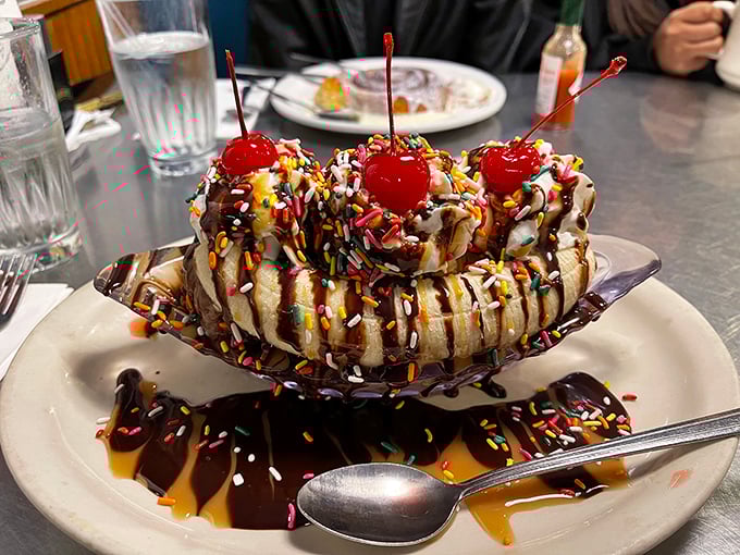 This banana split isn't just dessert—it's performance art. Those maraschino cherries standing tall amid sprinkle confetti deserve their own standing ovation.