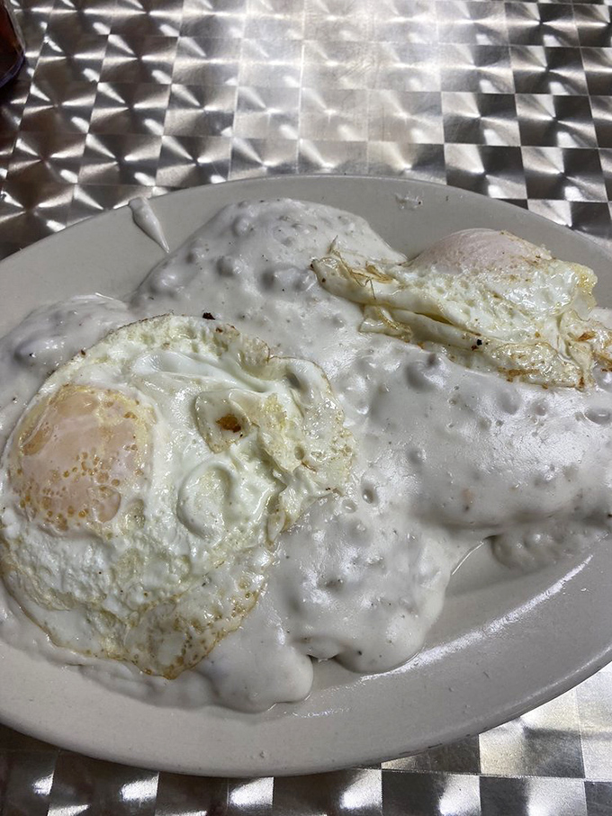 Eggs swimming in creamy sausage gravy—where breakfast meets art in a plate-sized canvas of delicious comfort.