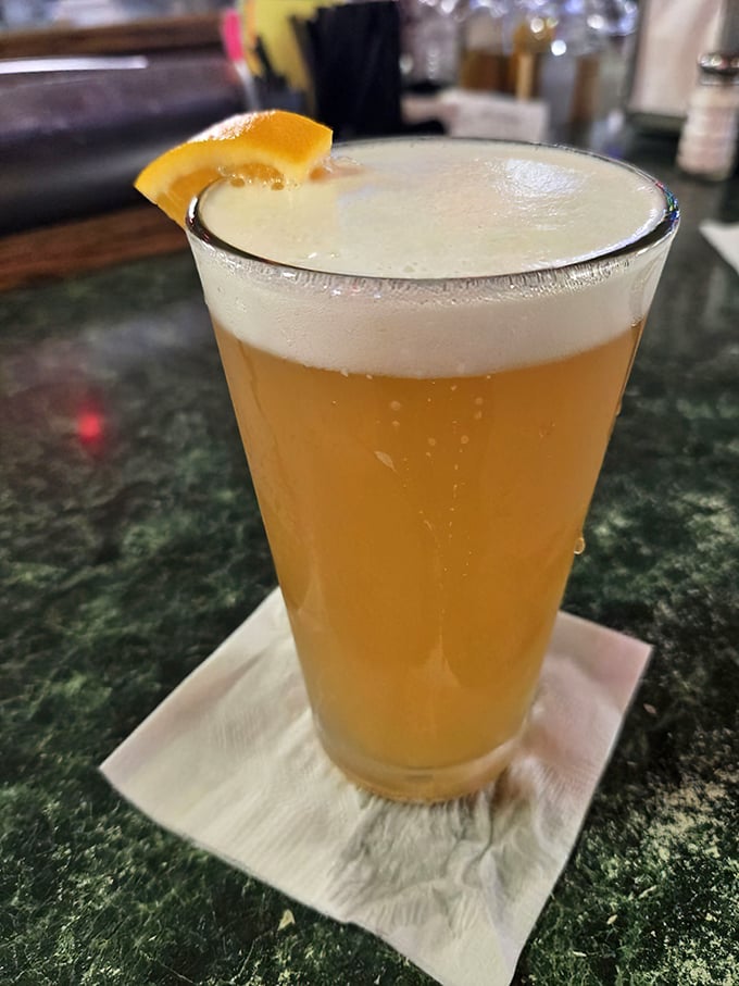 A perfectly poured beer with an orange slice perched on the rim – because sometimes the desert heat demands nothing less than golden, effervescent refreshment.