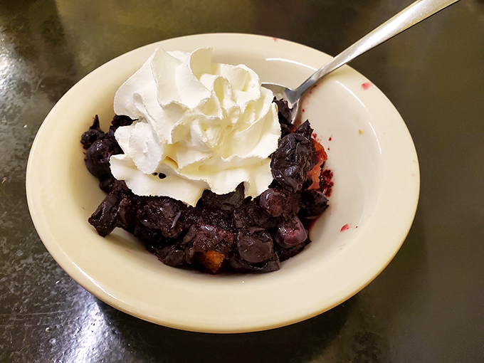 A bowl of blueberry cobbler topped with a cloud of whipped cream—proof that saving room for dessert is always the right decision.