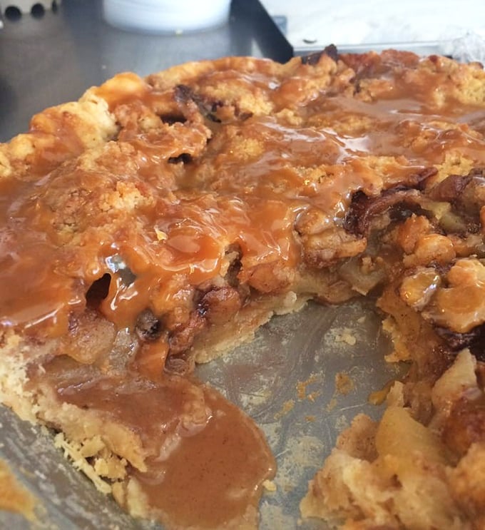 A slice of apple pie that's halfway to heaven – brown sugar crumble topping cascading into cinnamon-spiced apples and buttery crust below.