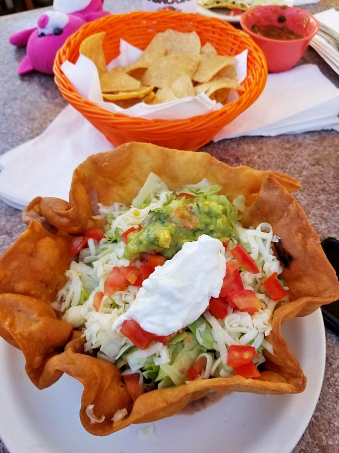 The humble chalupa transformed into an edible art form—a crispy, boat-shaped canvas painted with layers of lettuce, cheese, tomatoes, and creamy guacamole.