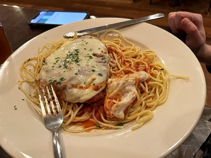 This chicken parmesan doesn't just sit on its pasta throne—it reigns supreme, melted cheese crown and all, ready for its fork-twirling close-up.
