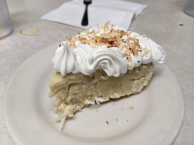 Coconut cream pie with a cloud of whipped cream and toasted coconut—the kind of dessert that makes you consider ordering a second slice before finishing the first.