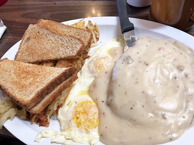 Country fried steak swimming in gravy with eggs standing by. This plate doesn't just feed you—it hugs your soul from the inside.