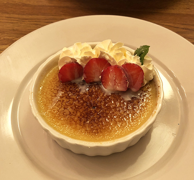The perfect crème brûlée sports a crackling sugar crust that shatters with satisfying resistance, revealing silky custard beneath—dessert engineering at its finest.