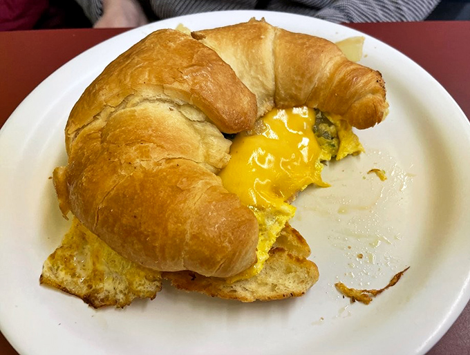That magical moment when yolk meets croissant – breakfast sandwich perfection achieved.