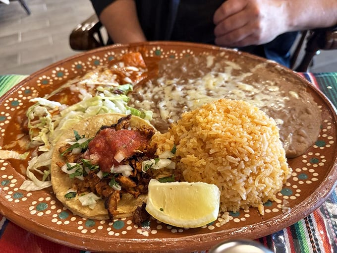 A perfect trifecta of taco, rice, and beans on a decorative plate – simple, authentic flavors that remind you why Mexican cuisine conquered America's heart.