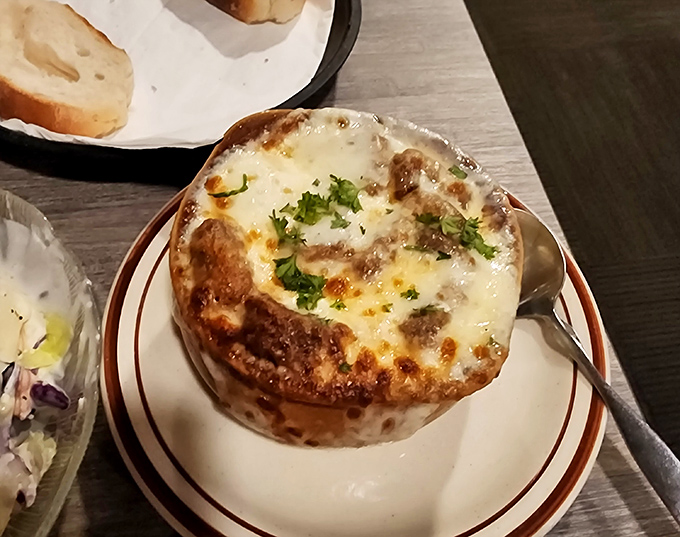 French onion soup that bubbles with promise under a golden cheese canopy. Breaking through the top is like discovering buried treasure—if treasure were made of cheese and onions.
