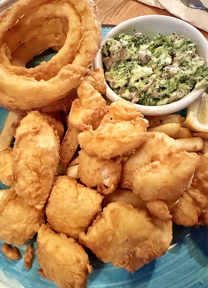 Golden-battered fish bites with crispy onion rings and creamy slaw—the kind of plate that makes conversation stop as everyone reaches for "just one more."