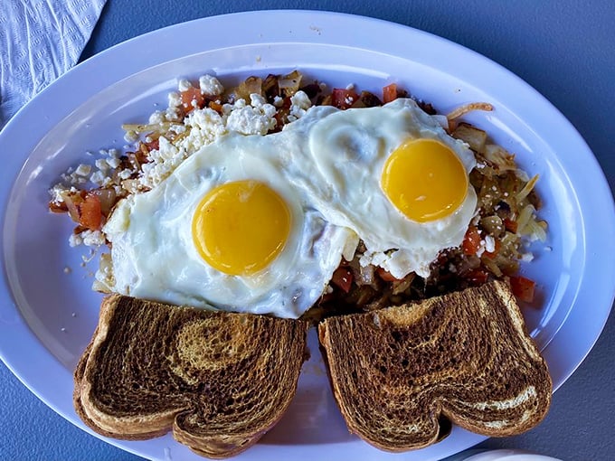 Two sunny eggs stand guard over a colorful skillet creation—a morning masterpiece that proves breakfast is the most important art of the day.