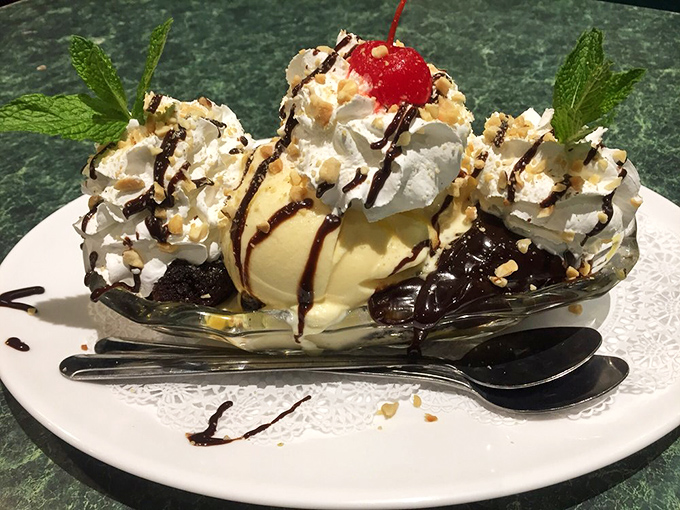 A hot fudge sundae that demands to be photographed. Vanilla ice cream, whipped cream mountains, chocolate drizzle, and that cherry on top—dessert architecture at its finest.