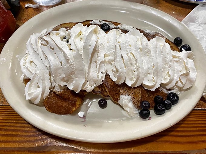 Pancakes topped with enough whipped cream to qualify as cloud surfing. Those blueberries are just trying to maintain the illusion that this is breakfast, not dessert.