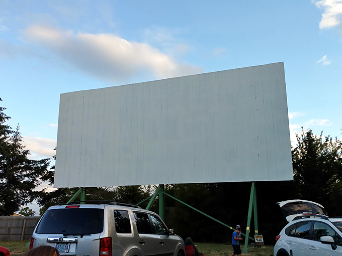 The massive white screen stands ready for its nightly transformation—from blank canvas to window into other worlds as cars gather below.