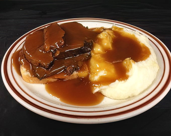 The open-faced roast beef sandwich—comfort food royalty wearing a crown of gravy. Mashed potatoes stand by, ready to soak up every delicious drop.