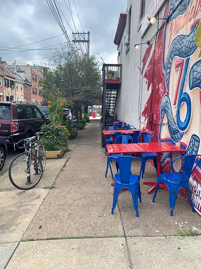 Outdoor seating with bold blue chairs against vibrant murals—Fishtown's artistic spirit meets diner practicality in this perfect urban tableau.