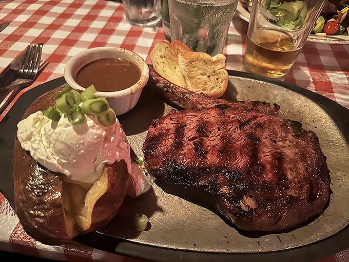 The ribeye arrives like a meaty promise fulfilled—charred exterior, rosy interior, with a baked potato sidekick that's dressed for the occasion.