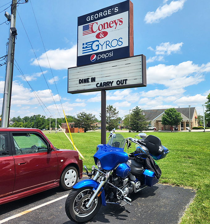 The roadside sign stands tall and proud, waving both American and Greek flags – a beacon for hungry travelers seeking cross-cultural comfort food.