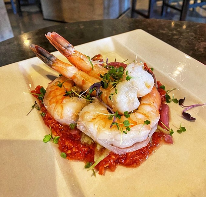 Shrimp so perfectly cooked they practically pose for their close-up, resting on a bed of vibrant sauce like celebrities on a red carpet. 