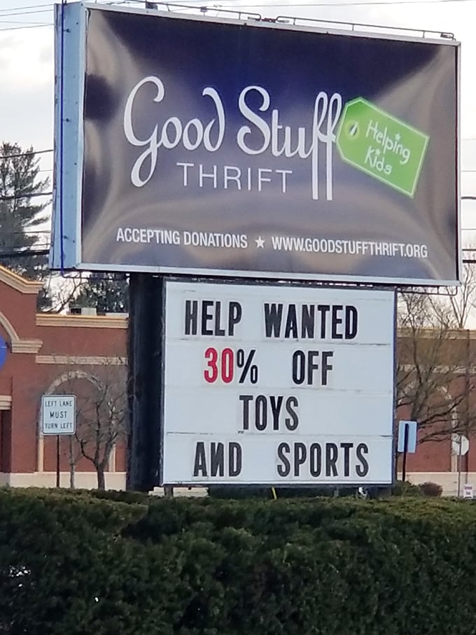 The roadside sign announces more than just a store—it's a beacon for bargain hunters and a reminder that shopping here helps kids.