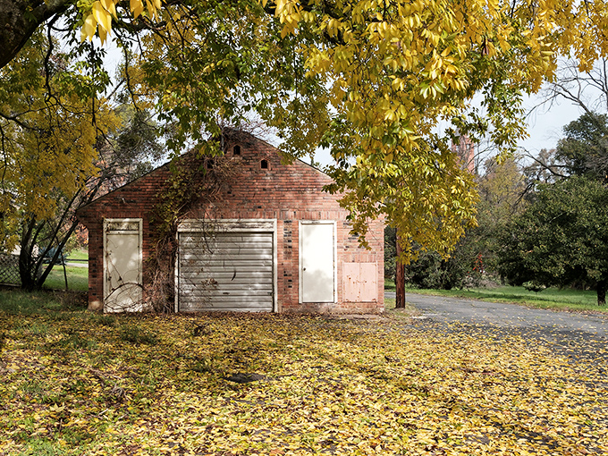 Autumn's golden carpet surrounds this humble brick building—a scene that whispers "affordable property taxes" to weary urban escapees seeking simpler living.