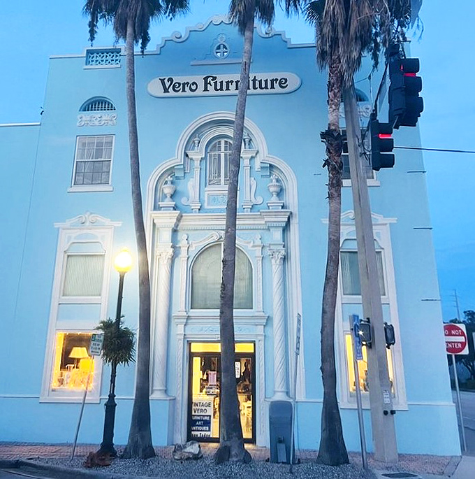 As evening falls, the historic façade glows with invitation, palm trees standing sentinel over decades of design history waiting inside.