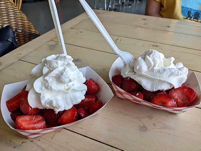 Fresh strawberries crowned with clouds of whipped cream—nature's perfect dessert that somehow tastes even better when eaten at a weathered wooden table.