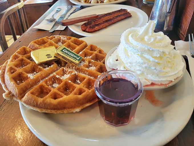 A waffle that's both crisp and tender, topped with whipped cream and served with real maple syrup—breakfast's perfect indulgence.
