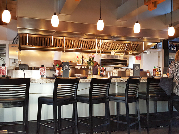 The bar area where strangers become friends over oyster shooters. Pendant lighting casts a warm glow that makes everyone look like they're on vacation.