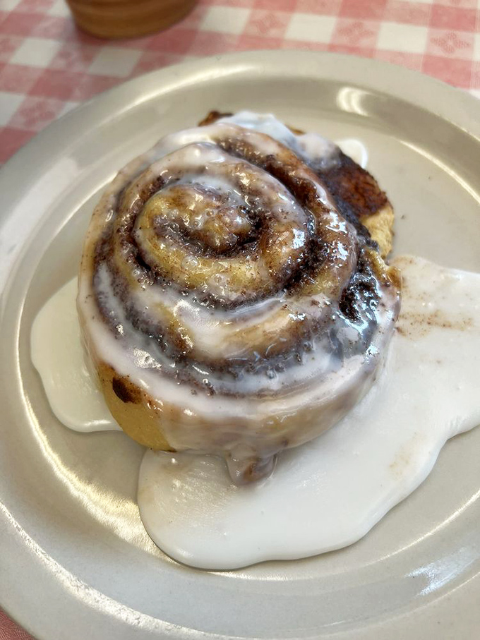 The cinnamon roll doesn't merely arrive—it makes a grand entrance, swimming in a pool of icing that transforms your coffee into the perfect supporting actor.