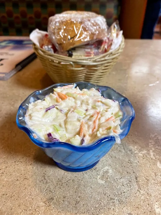 Cole slaw in its natural habitat—the blue scalloped bowl. This creamy, crunchy side dish patiently waits its turn while bread basket contents mysteriously disappear.