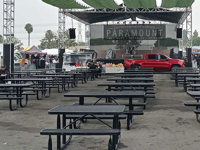 The entertainment heart of Paramount Swap Meet, where picnic tables await hungry shoppers under the watchful gaze of the drive-in screen.