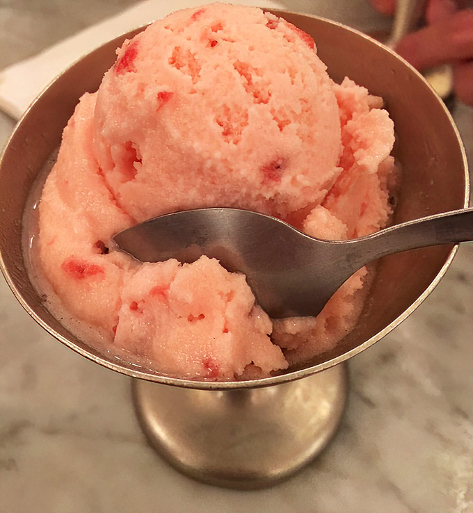 This strawberry scoop isn't just pink—it's the exact color of summer memories and childhood joy served in a silver dish.