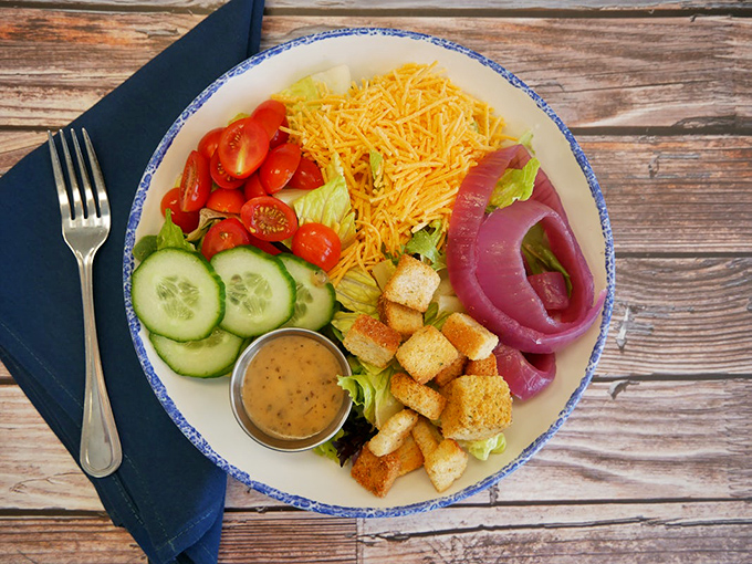 A house salad arranged with the precision of a color wheel artist—proof that vegetables can dress up for dinner too.