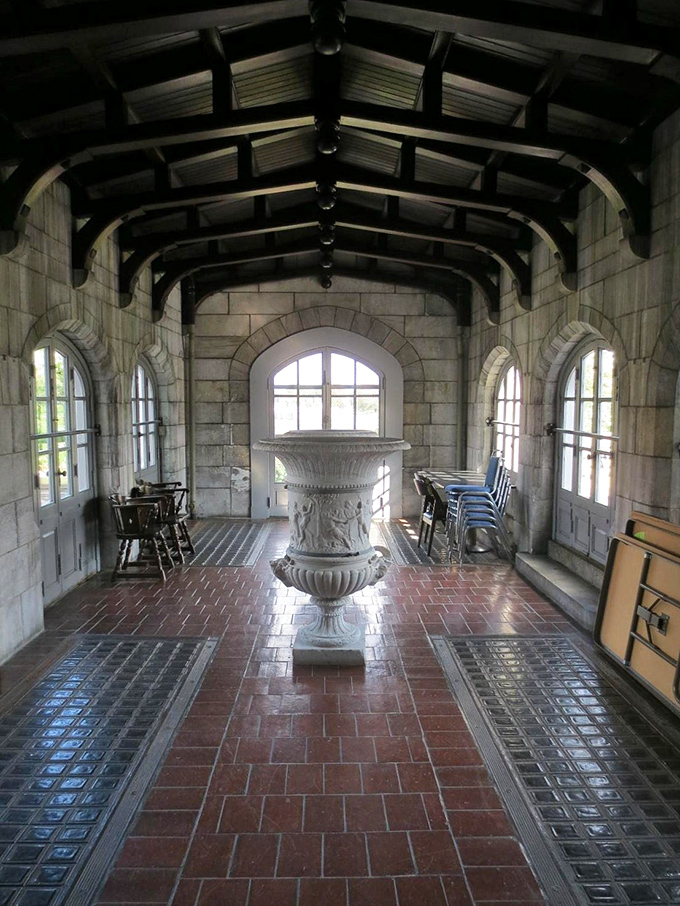 Arched windows flood this stone chamber with natural light, highlighting the classical urn that serves as the room's dramatic centerpiece.