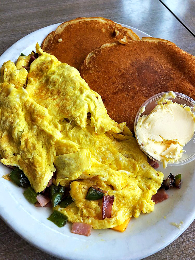 This isn't just an omelet—it's breakfast architecture, with perfectly folded eggs housing a treasure of colorful vegetables and melted cheese.