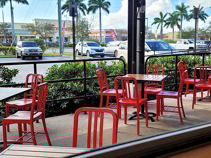 Outdoor seating where Florida's sunshine and barbecue's smoke create the perfect marriage. Those red chairs aren't just furniture—they're front-row seats to flavor town.