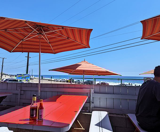 Ocean views from the patio make every bite taste better. Hot sauce bottles stand ready while umbrellas provide shade – they've thought of everything.