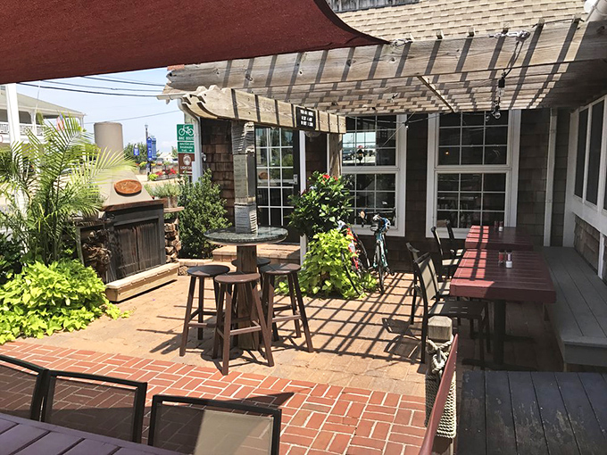 The outdoor patio—where salt air enhances every bite, and the pergola creates dancing shadows that make your cocktail taste even better.