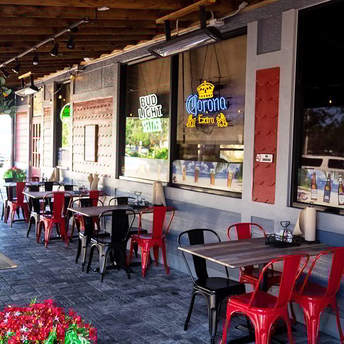 The outdoor seating area with those signature red chairs—where gentle Florida breezes enhance every bite and no one rushes you through your seafood bliss.