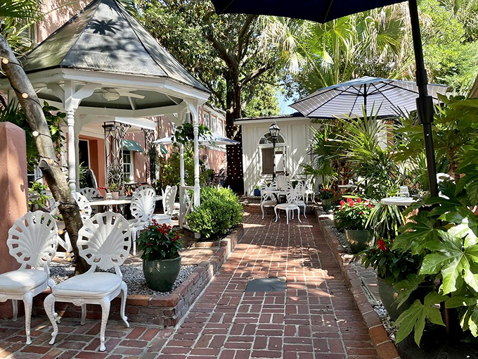The courtyard dining area is Charleston's worst-kept secret—dappled sunlight, brick pathways, and white garden furniture create an oasis in the historic district. 