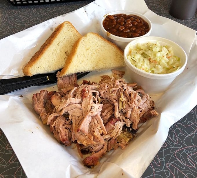 Pulled pork in its natural habitat—surrounded by white bread and sides. This isn't just a meal, it's a Southern handshake in food form.