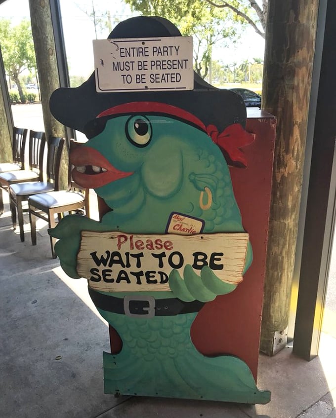 Captain Fish welcomes you with a smile and a sign. This seafood sentry ensures you'll be seated promptly for your underwater feast.