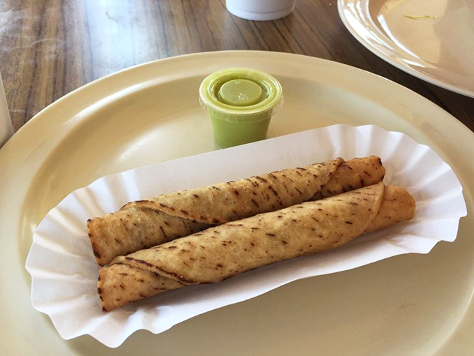 Crispy taquitos served with a vibrant green sauce—proof that simple food done right is worth more than a thousand deconstructed culinary experiments.