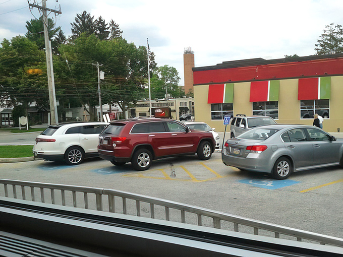 The view from inside captures life in motion—cars coming and going in the parking lot, a reminder that a great diner is always at the center of community life.
